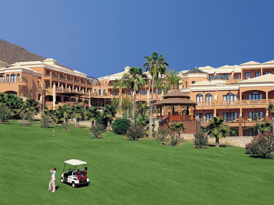 Um campo de golfe com um clube e um edifício com várias varandas e um coreto.