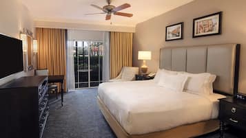 Quarto de hotel com uma cama grande, televisão, escrivaninha e cadeira.