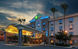 Um hotel Holiday Inn Express & Suites com design moderno, apresentando uma entrada coberta e vários andares.