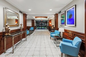 Um saguão de hotel com balcão de recepção, área de estar e vista para o interior do hotel.