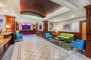 Um saguão de hotel com balcão de recepção, área de estar e uma grande janela.