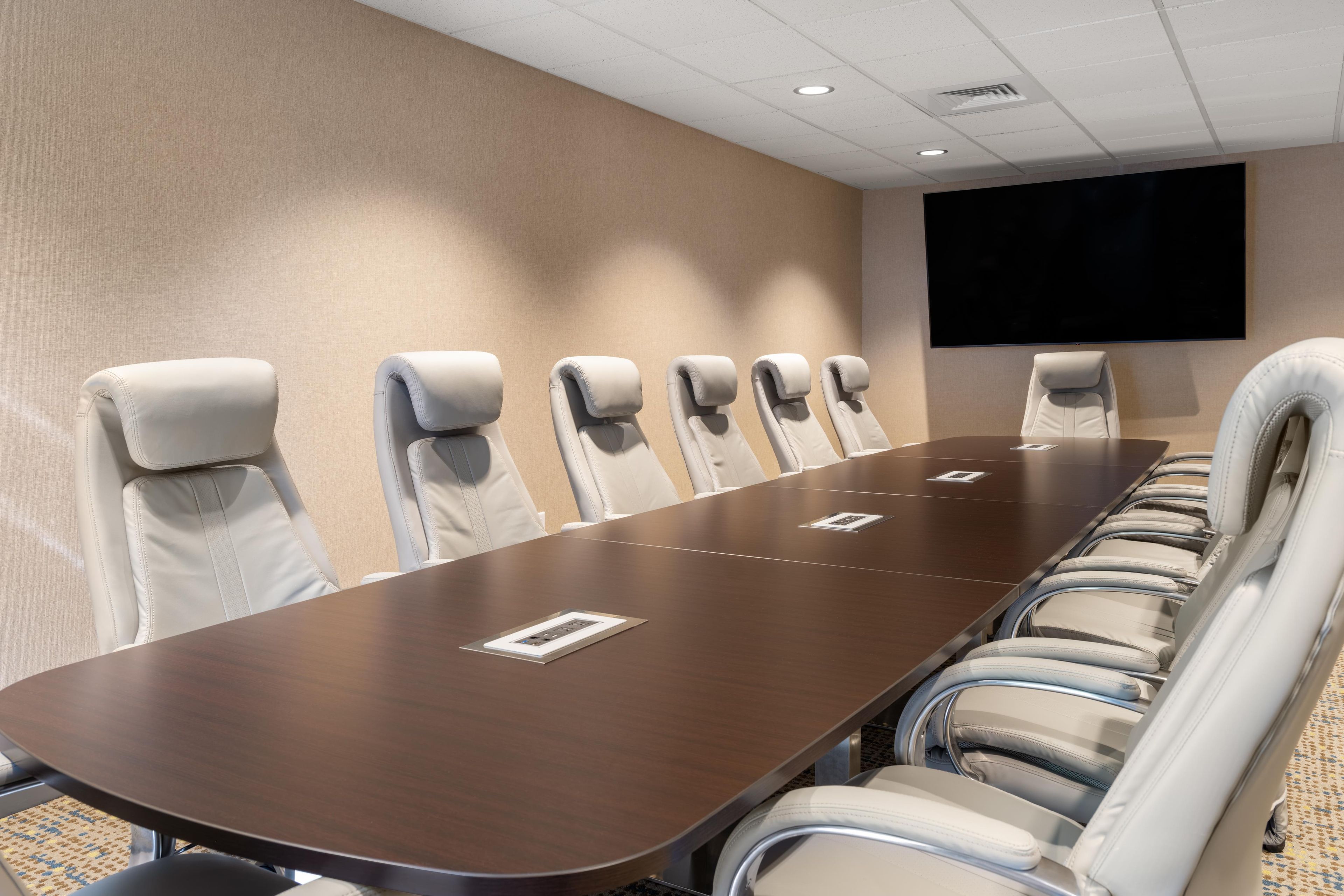 Uma sala de conferências com uma mesa comprida e seis cadeiras estofadas.