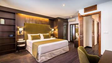 Quarto de hotel moderno com uma cama grande, uma mesa de cabeceira, uma cadeira, uma escrivaninha e um guarda-roupa.