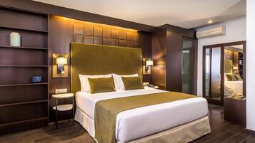 Quarto de hotel moderno com uma cama grande, estantes embutidas, abajures e um espelho.