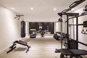 Uma academia com diversos equipamentos de exercícios, incluindo um saco de pancadas, esteira e aparelhos de musculação.