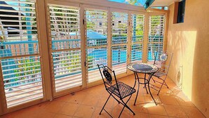 Estar coberto com vista para a piscina, com mesa e duas cadeiras.