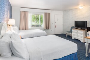 Quarto de hotel com duas camas, televisão, secretária e janela com cortinas.