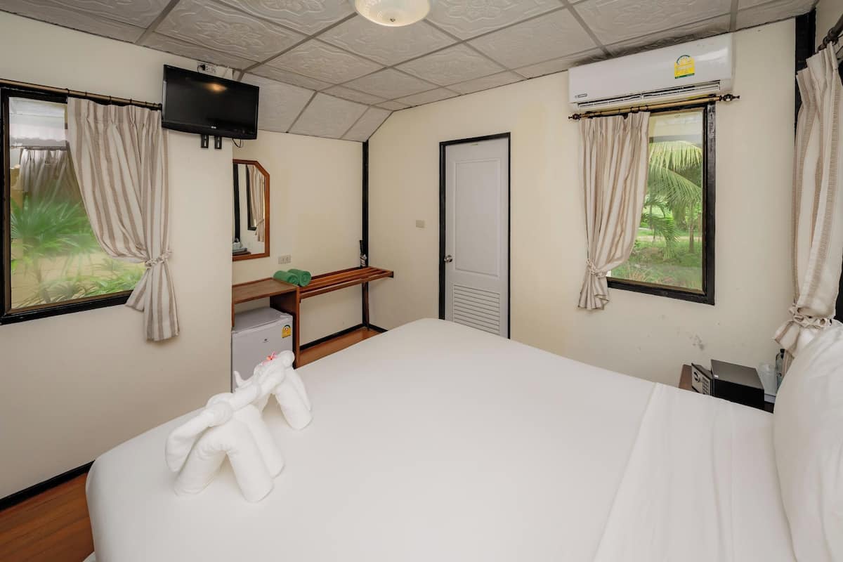 Quarto de hotel com uma cama, uma mesa, uma televisão, ar condicionado e cortinas.
