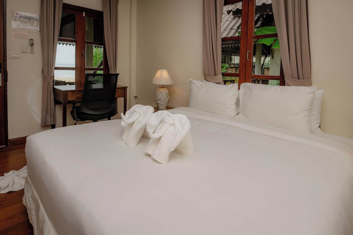 Quarto de hotel com cama, escrivaninha, cadeira e abajur.