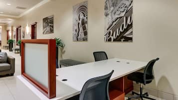 Um espaço de escritório moderno com uma mesa branca comprida, cadeiras de escritório pretas e obras de arte em preto e branco emolduradas nas paredes.
