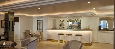 Uma área de bar com banquetas, balcão e diversas garrafas.