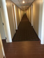 Um corredor comprido e estreito com carpete estampado e paredes brancas.