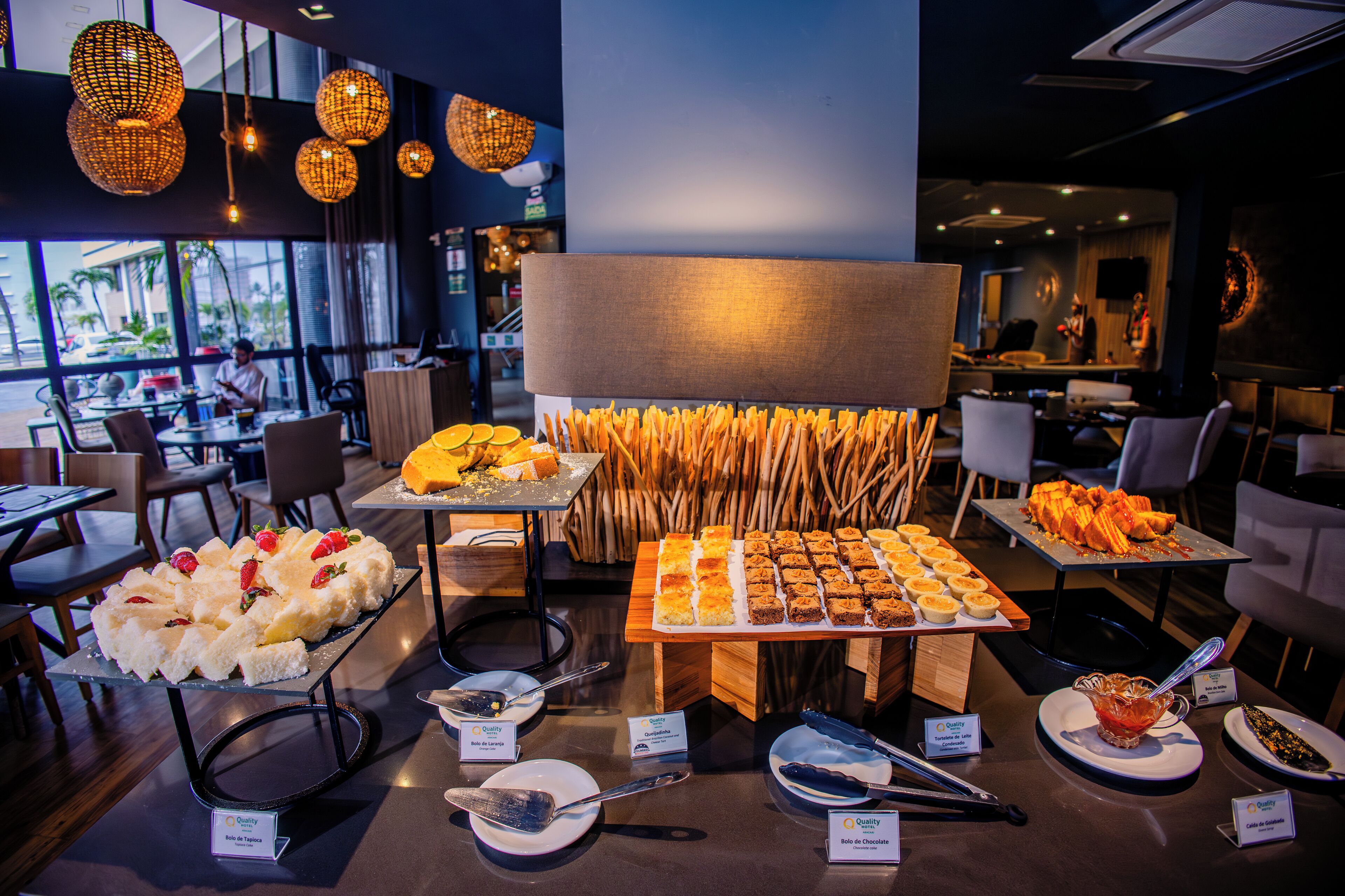 Buffet com diversos doces e área de estar com mesas e cadeiras.