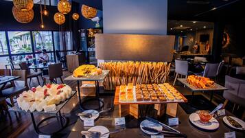 Buffet com diversos doces e área de estar com mesas e cadeiras.
