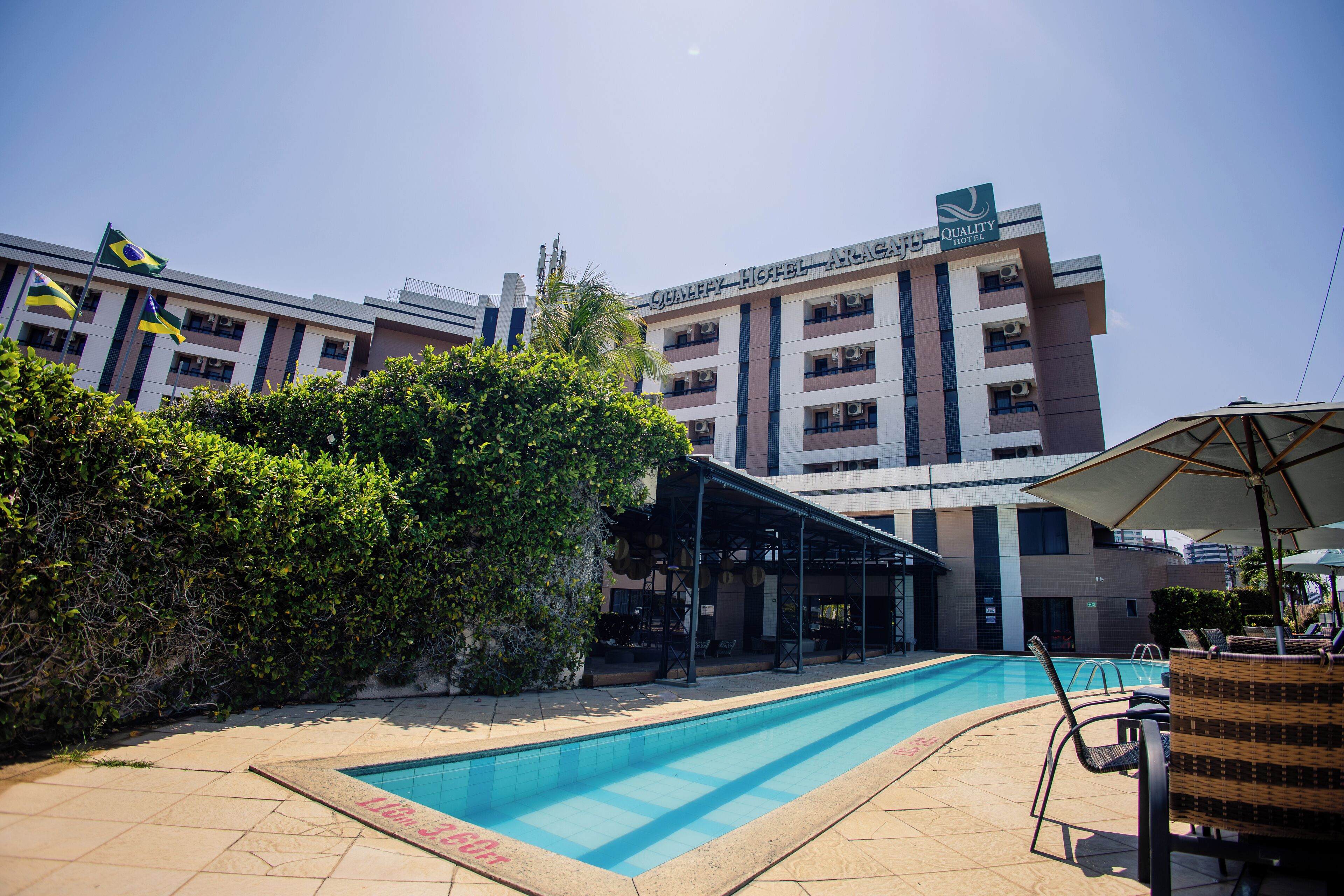 Um hotel com piscina, área de estar externa e espaço coberto.