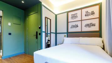 Quarto de hotel com cama, espelho, guarda-roupa e obras de arte na parede.
