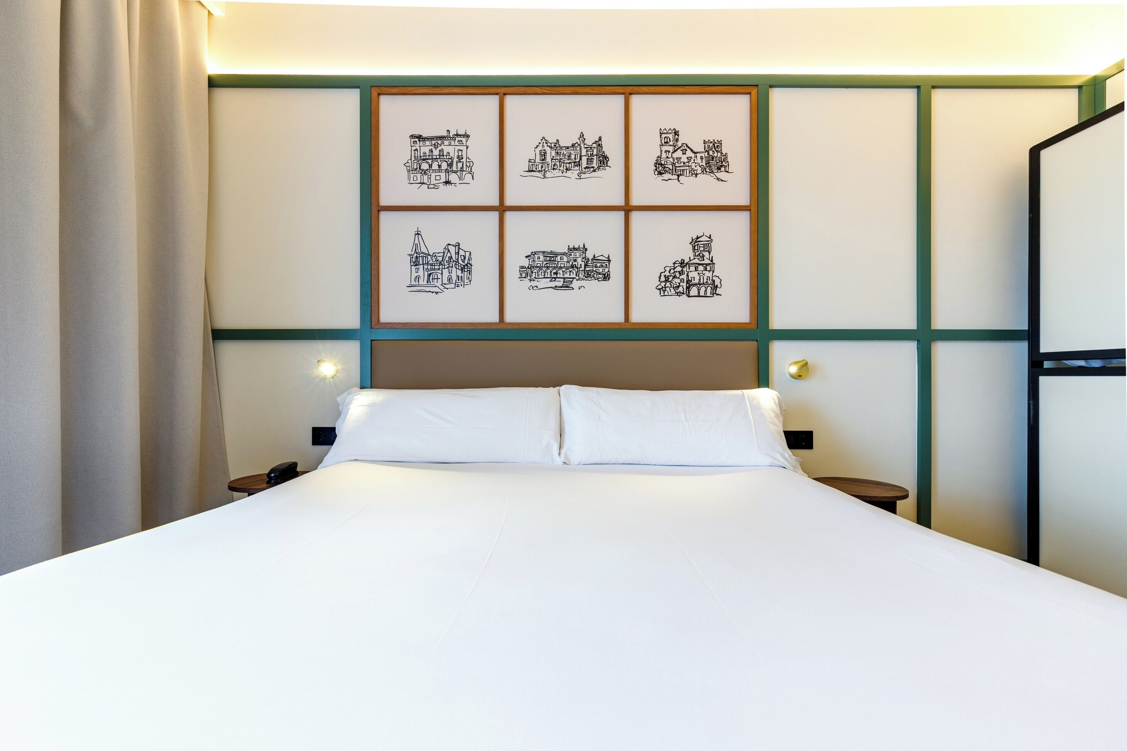 Quarto de hotel com uma cama grande, duas mesas de cabeceira, cabeceira com arte e uma cortina à esquerda.
