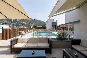 Terraço no telhado com piscina, área de estar ao ar livre e vista para uma colina.