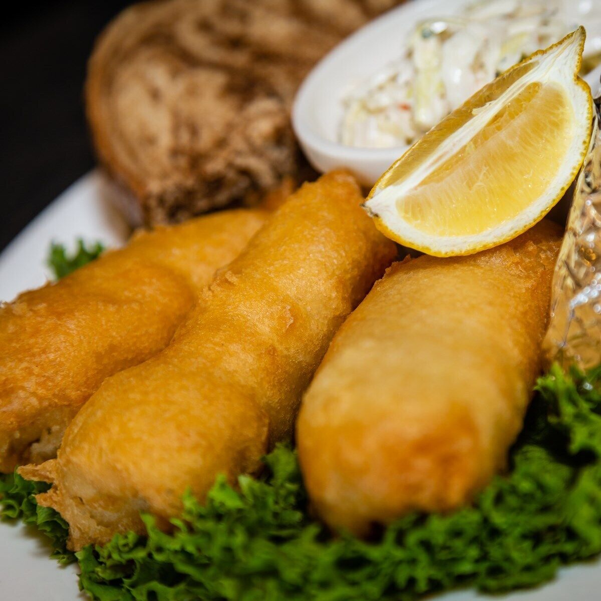 Um prato de peixe frito, uma salada e uma fatia de limão.