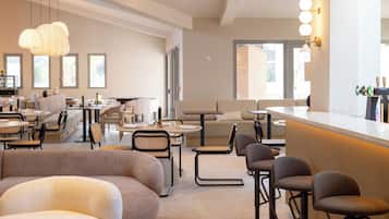 Uma área de refeições moderna com mesas redondas, banquetas e um balcão de bar.