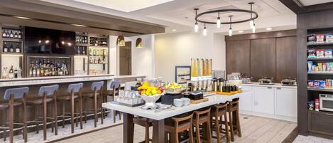 Uma cozinha moderna com área de bar, equipada com banquetas, uma fruteira e diversos eletrodomésticos.