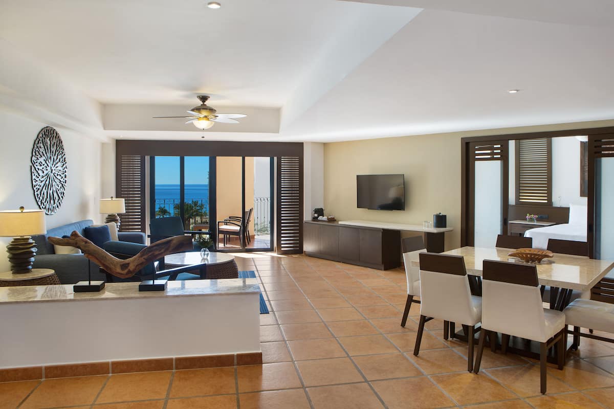 Uma sala de estar espaçosa com uma mesa de jantar, cadeiras, um sofá e uma televisão.