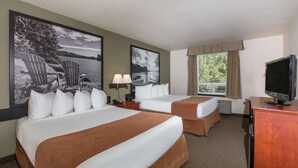 Quarto de hotel com duas camas, televisão, escrivaninha e obras de arte nas paredes.