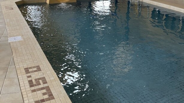 Piscina com escorregador em espiral, área de estar interna e piso revestido.
