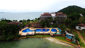 Um resort com várias piscinas, uma praia e vista para o mar.