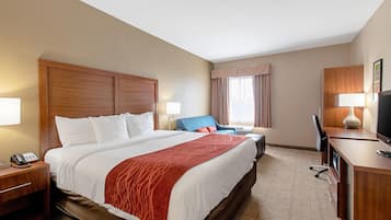 Quarto de hotel com cama grande, escrivaninha, cadeira, televisão e janela com cortinas.