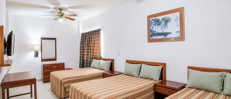 Quarto de hotel com duas camas, uma escrivaninha, televisão, ventoinha no teto e um quadro na parede.