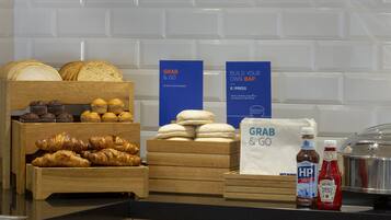 Buffet de café da manhã com pães, doces e acompanhamentos.