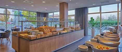 Um rico buffet de café da manhã com diversas opções de comida, área de estar e amplas janelas com vista para o exterior.