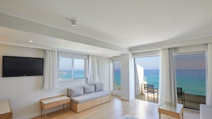 Quarto de hotel moderno com uma cama grande, um sofá, uma escrivaninha e uma varanda com vista para o mar.