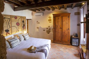 Quarto com cama, guarda-roupa de madeira, parede decorada com pedras e ar condicionado.