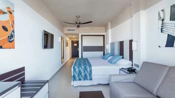 Quarto de hotel moderno com cama, sofá, escrivaninha e ventilador de teto.