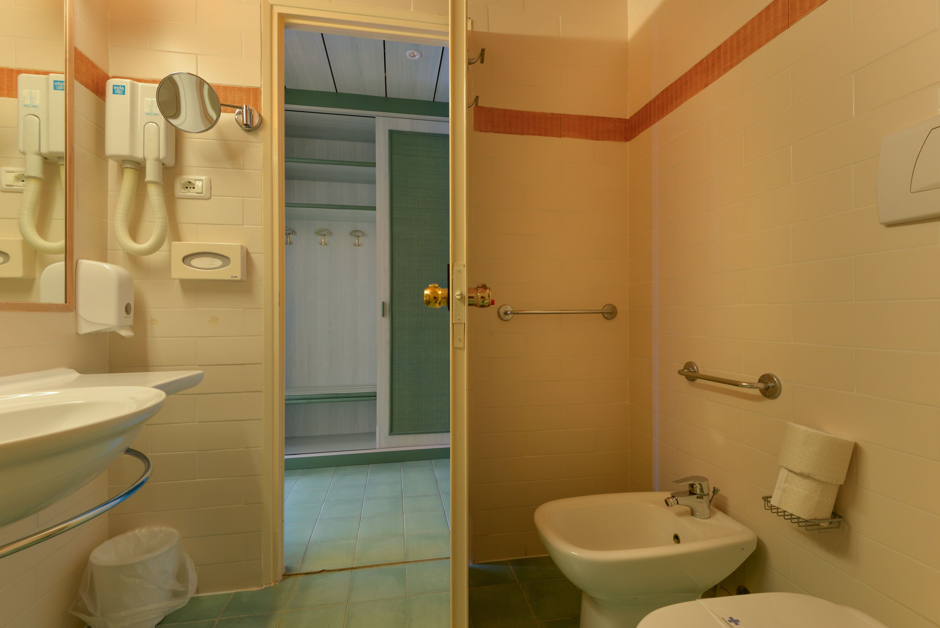 Uma casa de banho com lavatório, bidé e sanita. Tem um espelho e um porta-toalhas.