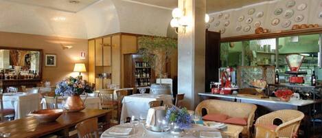 Uma sala de jantar com mesas e cadeiras de madeira, e um balcão de buffet.
