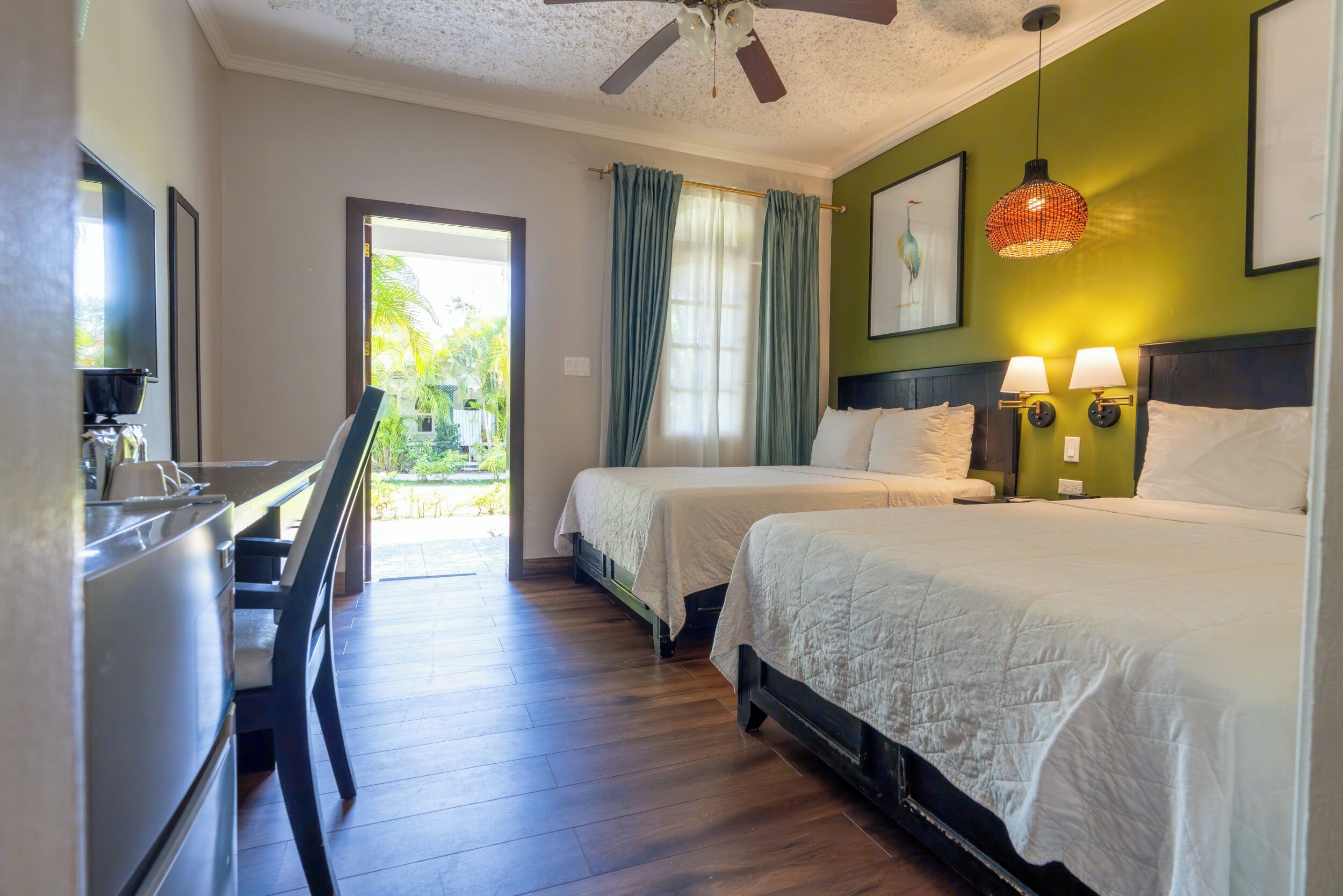 Quarto de hotel com cama, abajures, ventoinha no teto e vista para o exterior.