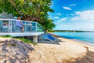 Na praia, areia branca, espreguiçadeiras, guarda-sóis
