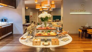 Disposição de buffet com diversos alimentos e um arranjo floral central sobre uma mesa de mármore.