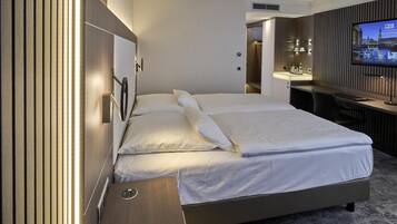 Quarto de hotel moderno com uma cama grande, uma escrivaninha e uma televisão.