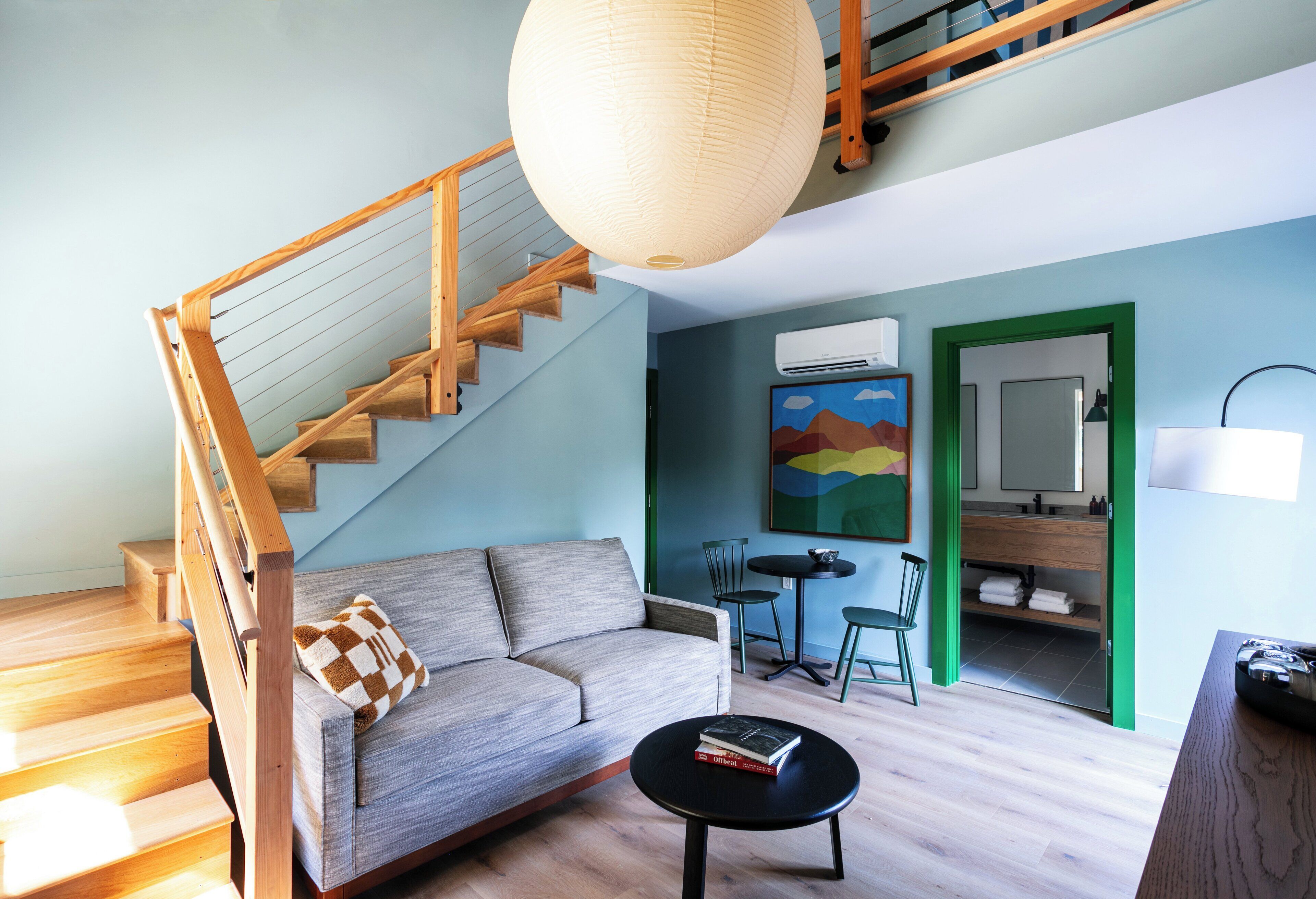 Uma sala de estar moderna com escada, um sofá, uma mesa de centro e um espaço para refeições.