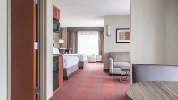 Quarto de hotel com cama, escrivaninha, cadeira, mesa e piso coberto por carpete.