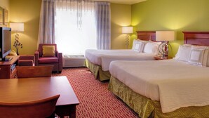 Quarto de hotel com duas camas, uma escrivaninha, uma cadeira, uma televisão e uma janela com cortinas.