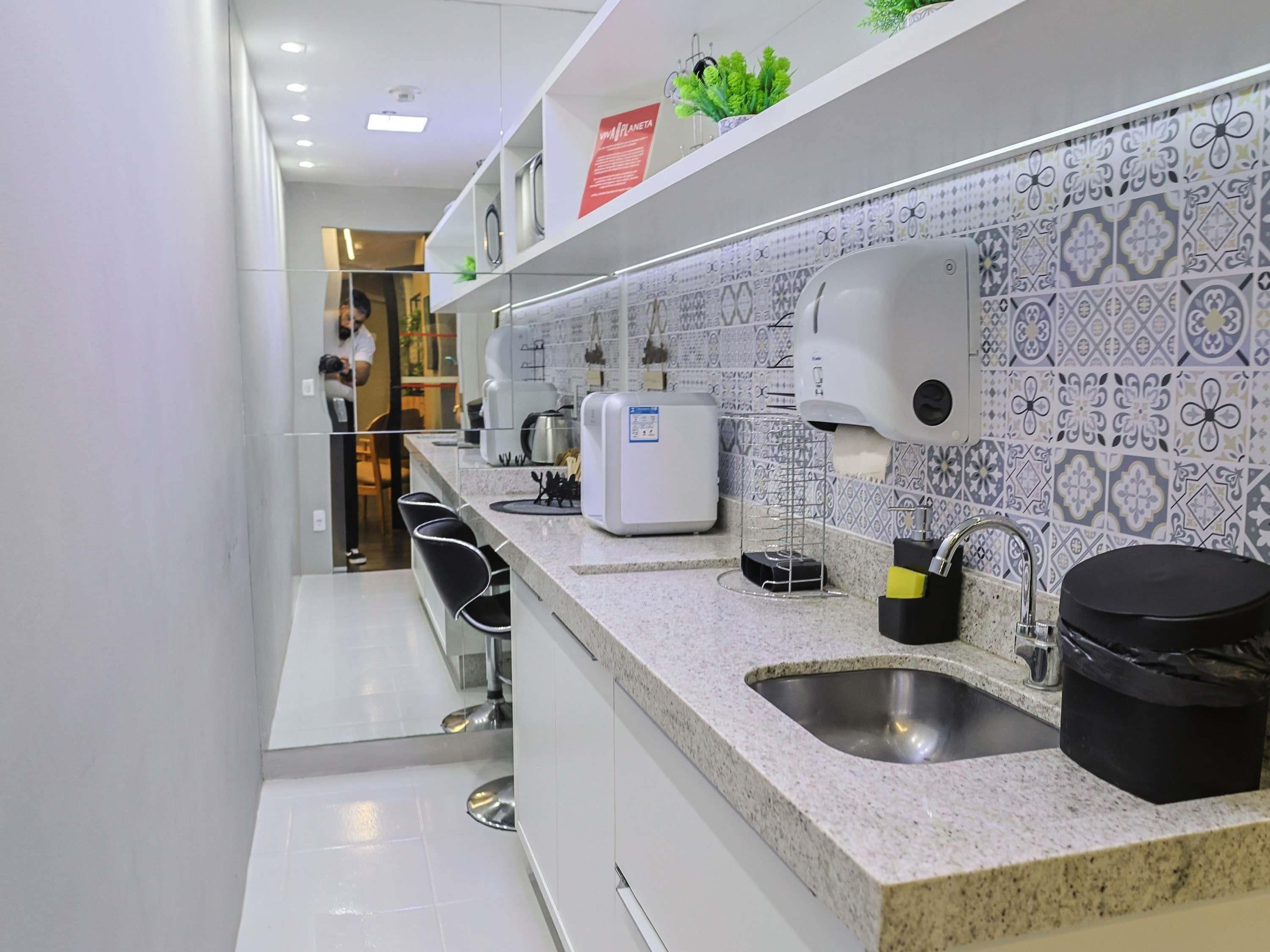Uma cozinha moderna com bancada de granito, pia de aço inoxidável e dosador de sabão embutido.