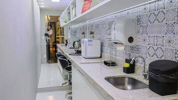 Uma cozinha moderna com bancada de granito, pia de aço inoxidável e dosador de sabão embutido.