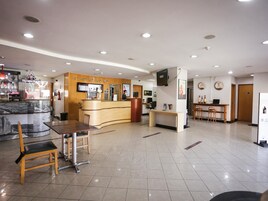 Um saguão de hotel com balcão de recepção, área de bar e disposição de assentos.