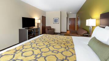Quarto de hotel com uma cama grande, televisão, escrivaninha com abajur e uma cadeira.