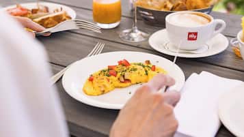 Uma mesa de café da manhã com ovos mexidos, um copo de suco de laranja, um croissant e uma xícara de café.